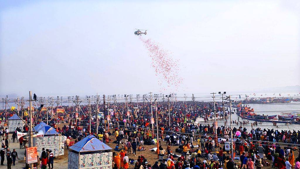 A helicopter showers flower petals at the Triveni Sangam