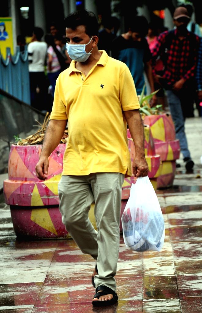 A man carrying a clothes bag walks past