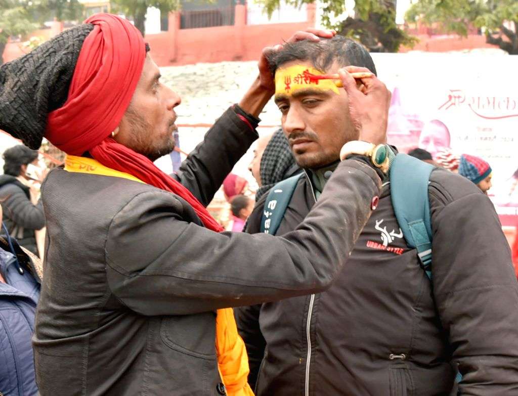 A man is writing 'Shri Ram' on the forehead of another devotee ahead of ...