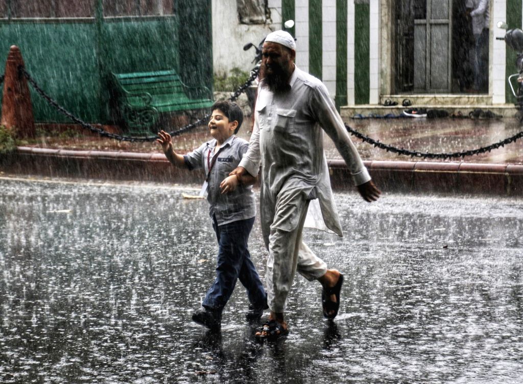 A man with a boy walks past during heavy rain