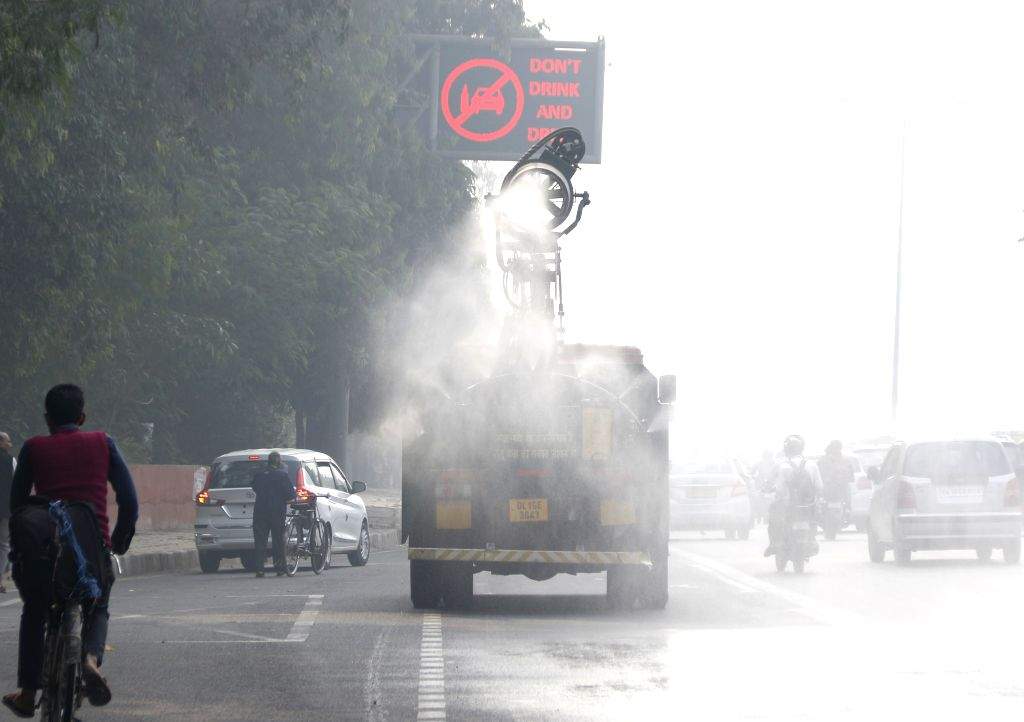 A municipal vehicle sprays water to settle dust on a road as part of ...