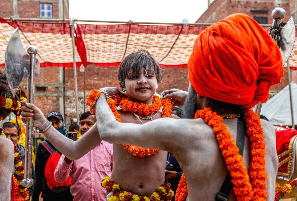 A Naga Sadhu places garlands on a child during a religious procession