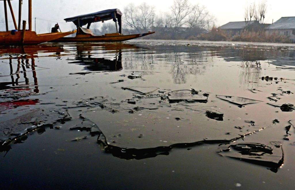A partially frozen Dal Lake with sheets of ice visible on the water