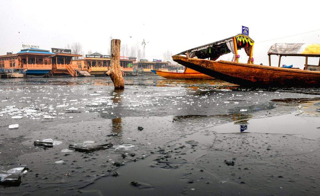 A partially frozen Dal Lake with sheets of ice visible on the water