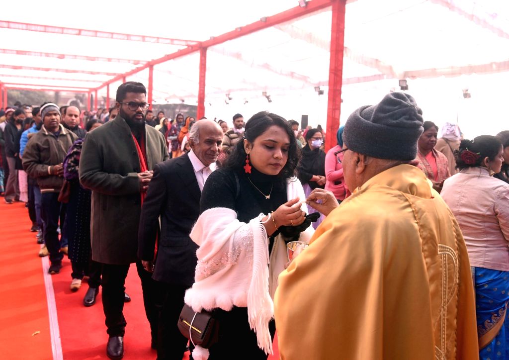 A priest gives sacramental bread to devotees
