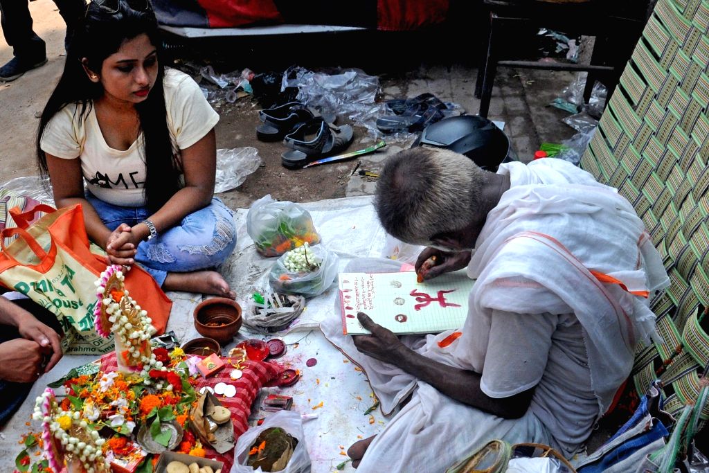 A priest writes in a 'Haal Khata' (accounting book) for traders