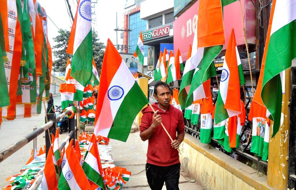 A street vendor displays the Tiranga (National Flag) for sale on a footpath