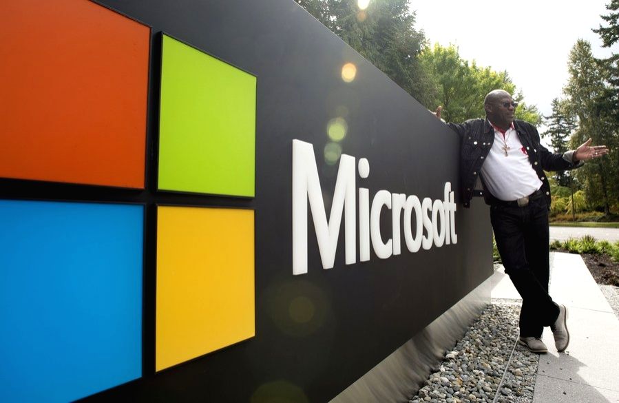 A visitor poses for a photo with Microsoft's logo at Microsoft's ...