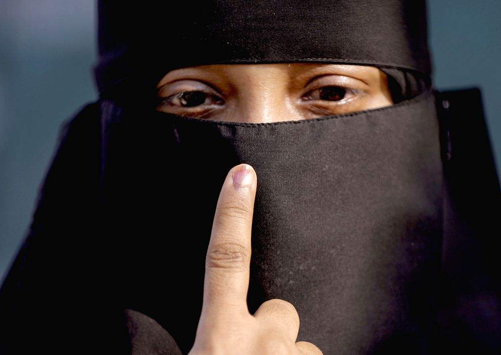 A voter shows her finger marked with indelible ink after casting her vote