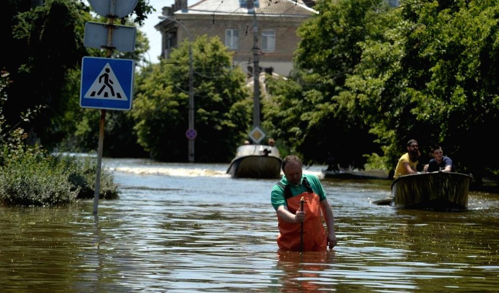A water conservancy worker measures water level on a flooded road in ...