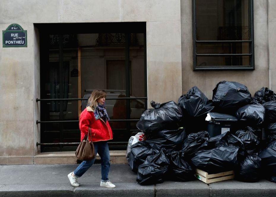 A woman walks past garbage left on the street near the Eiffel Tower in Pari
