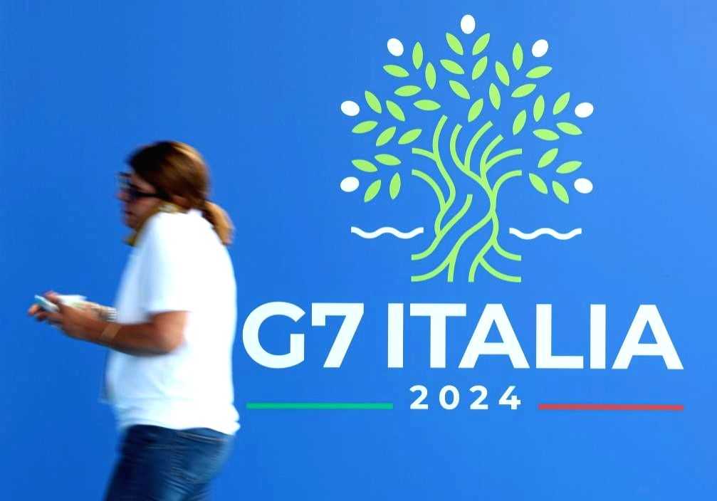 A woman walks past the banner of the Group of Seven (G7) summit at the ...