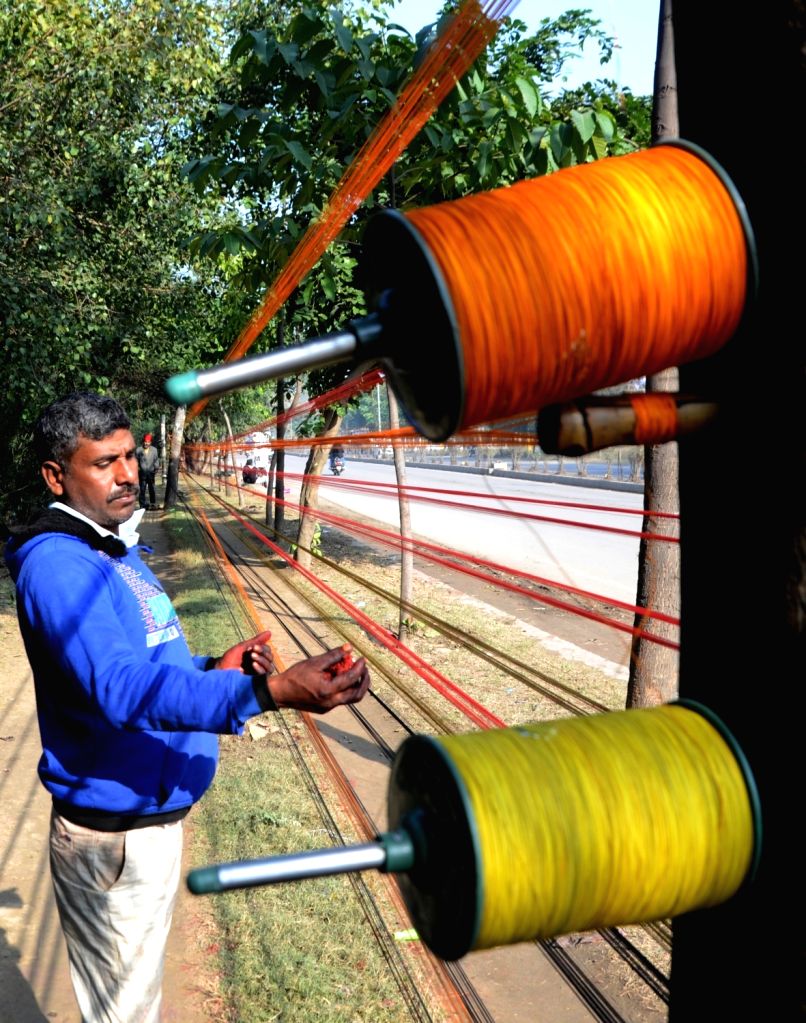A worker prepares coloured kite threads along the roadside ahead of the ...