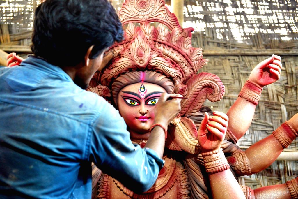 An artist gives final touches to an idol of Goddess Durga