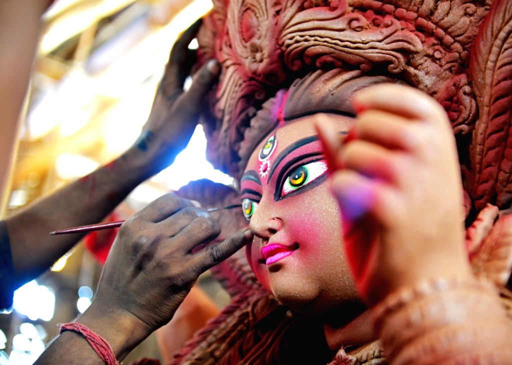 An artist gives final touches to an idol of Goddess Durga