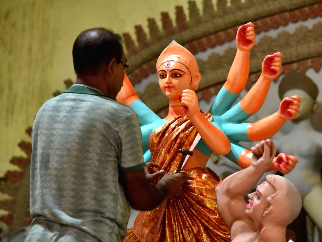 An artist giving final touches to an idol of Goddess Durga