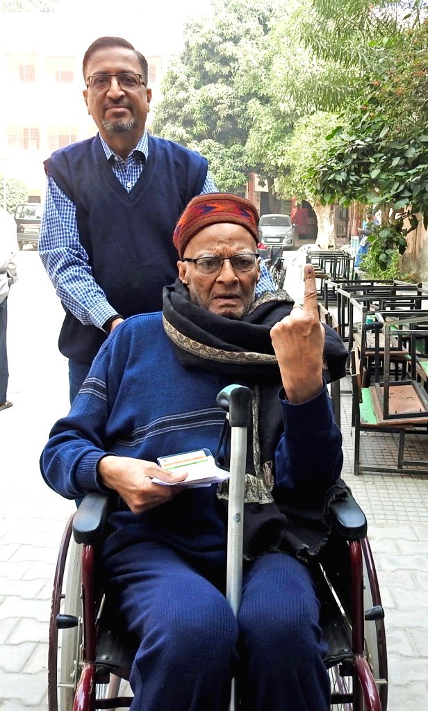 An elderly voter shows his finger marked with indelible ink after ...