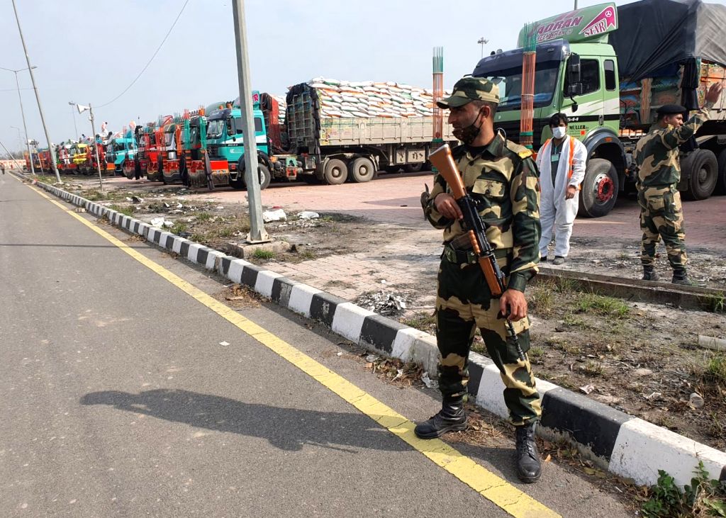 Armed Security personnel stand guard in front of loaded Trucks with ...