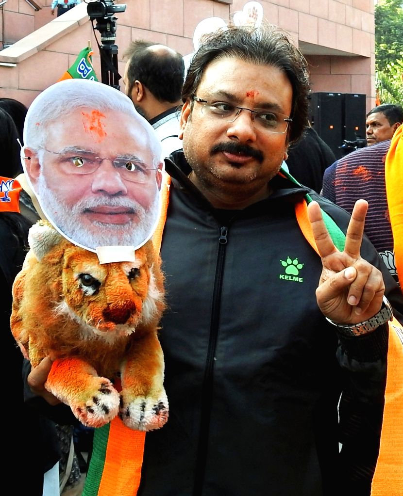 BJP worker holds a cut-out of PM Modi celebrating the party's victory