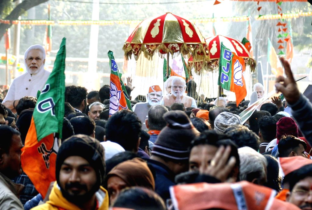 BJP workers and supporters hold cut-outs of PM Modi during a roadshow