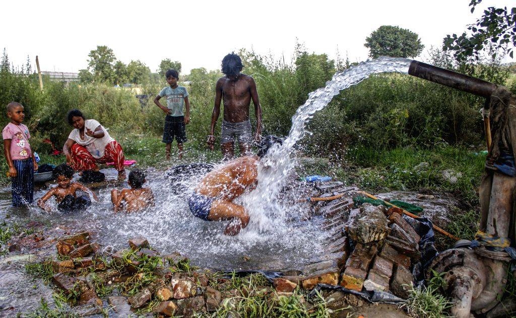 Boys taking a bath at a tubewell to beat the heat on a hot summer day