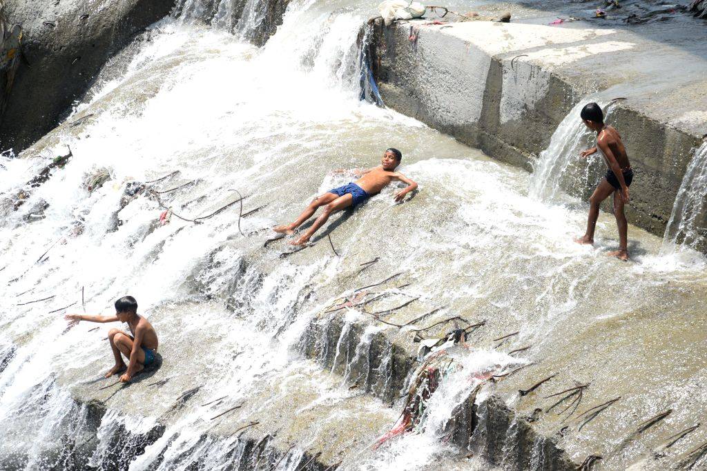 Children Cool Off in Water Stream Amid Heatwave
