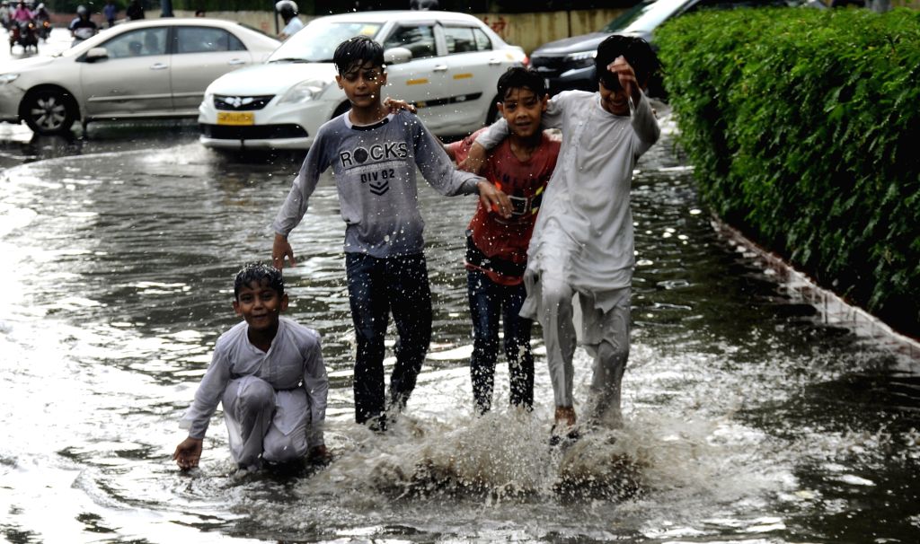 Children play on a waterlogged road after heavy rainfall