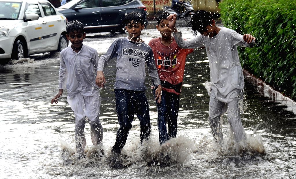 Children play on a waterlogged road after heavy rainfall