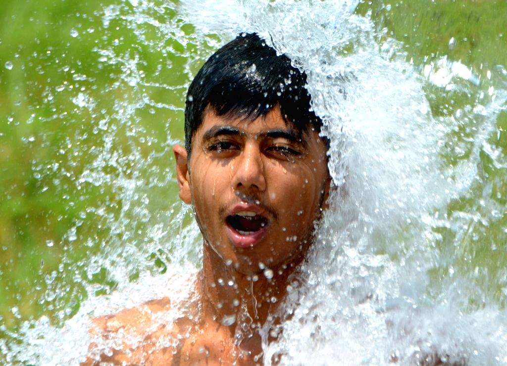 Children seek respite from rising temperatures by cooling off under a ...
