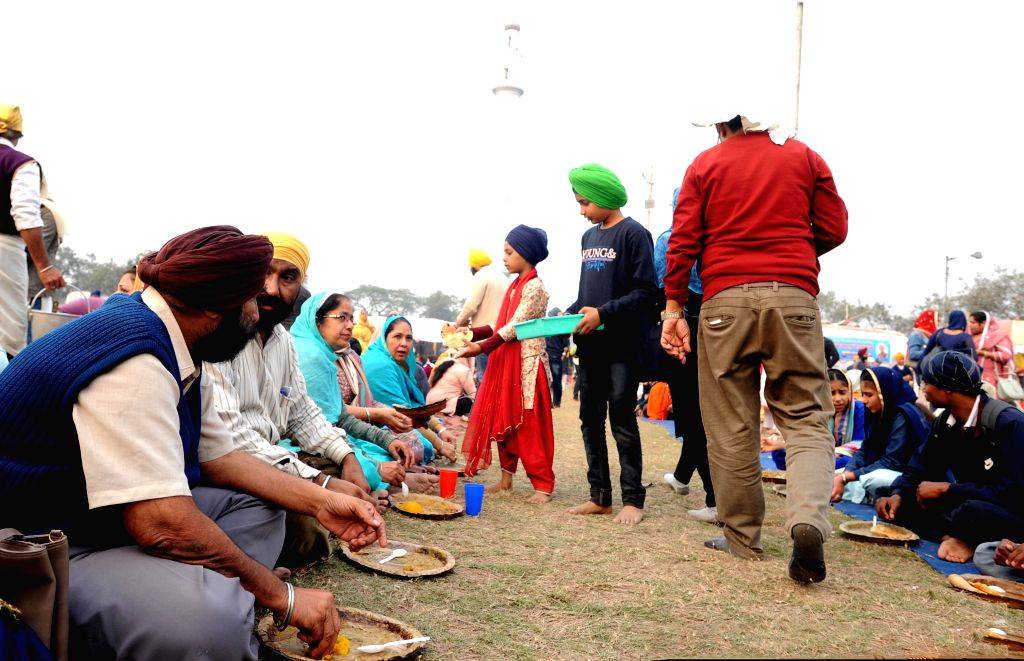 Children serve food during a 'langar' organised on the birth ...