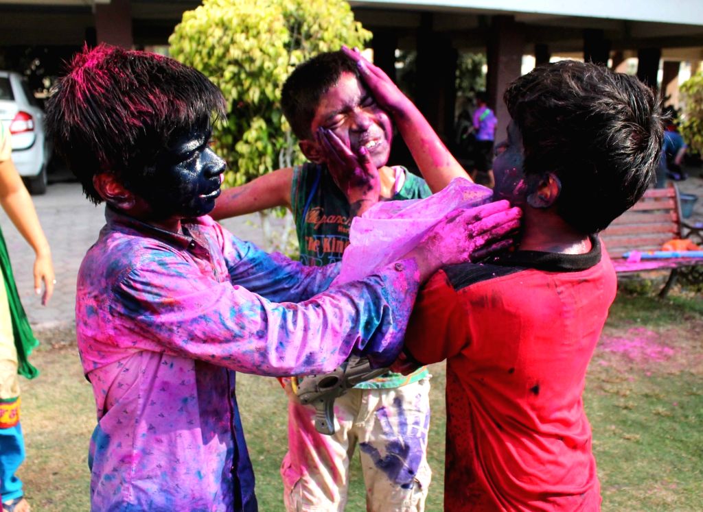 Children smear colours on each others face as they celebrate Holi in ...
