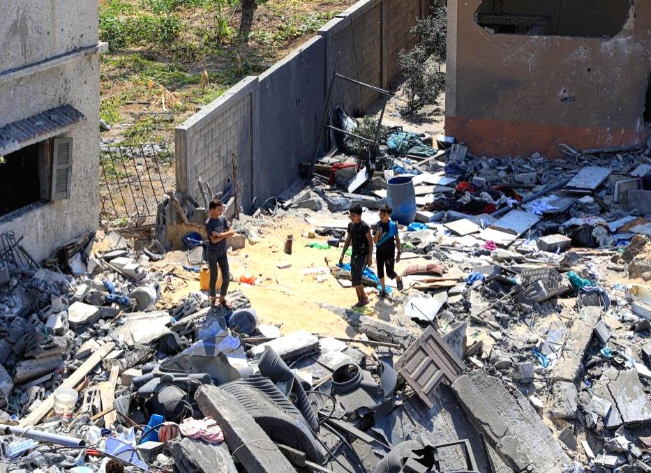 Children stand on the rubbles of a house damaged by Israeli airstrike ...