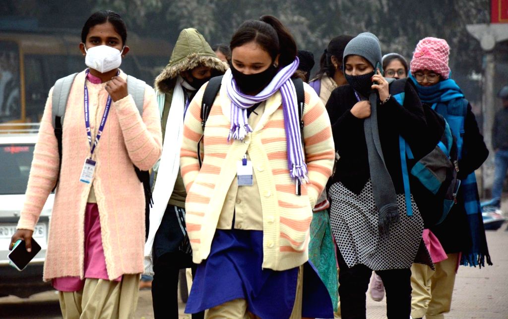 College students wearing warm clothes walk past on a cold and foggy day