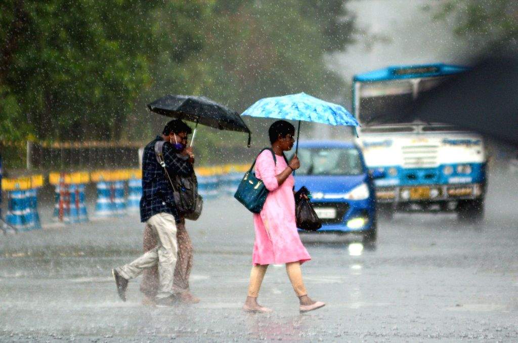 Commuters are seen crossing the road amid heavy rains