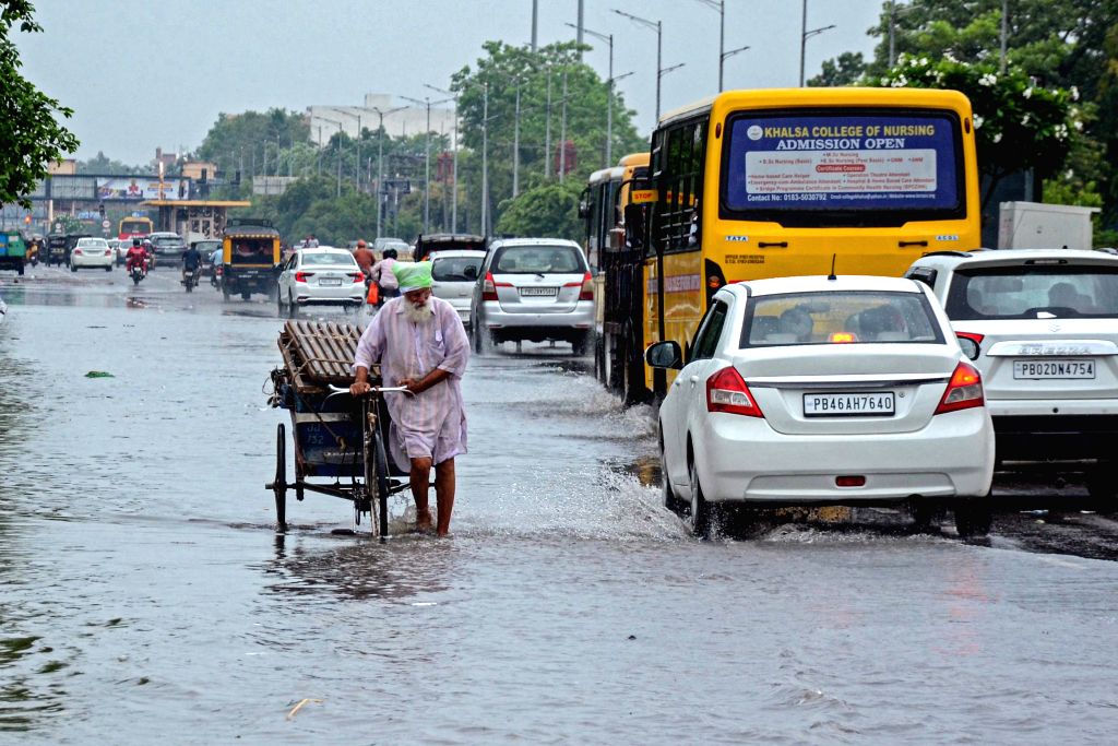 Commuters make their way through a water-logged street after rain