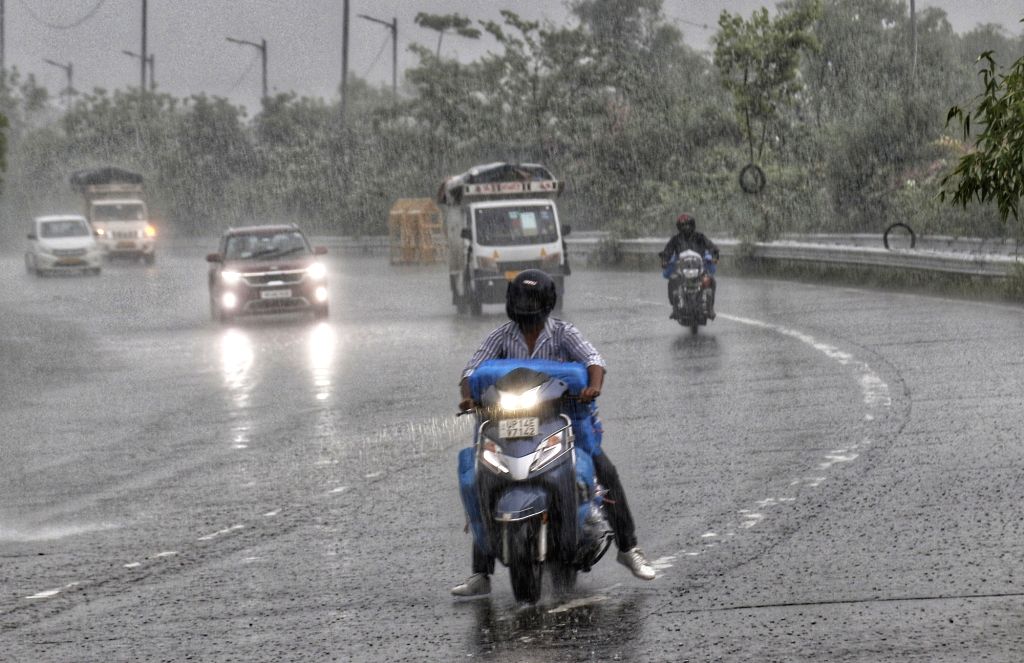 :New Delhi:Commuters move on road during monsoon rains.