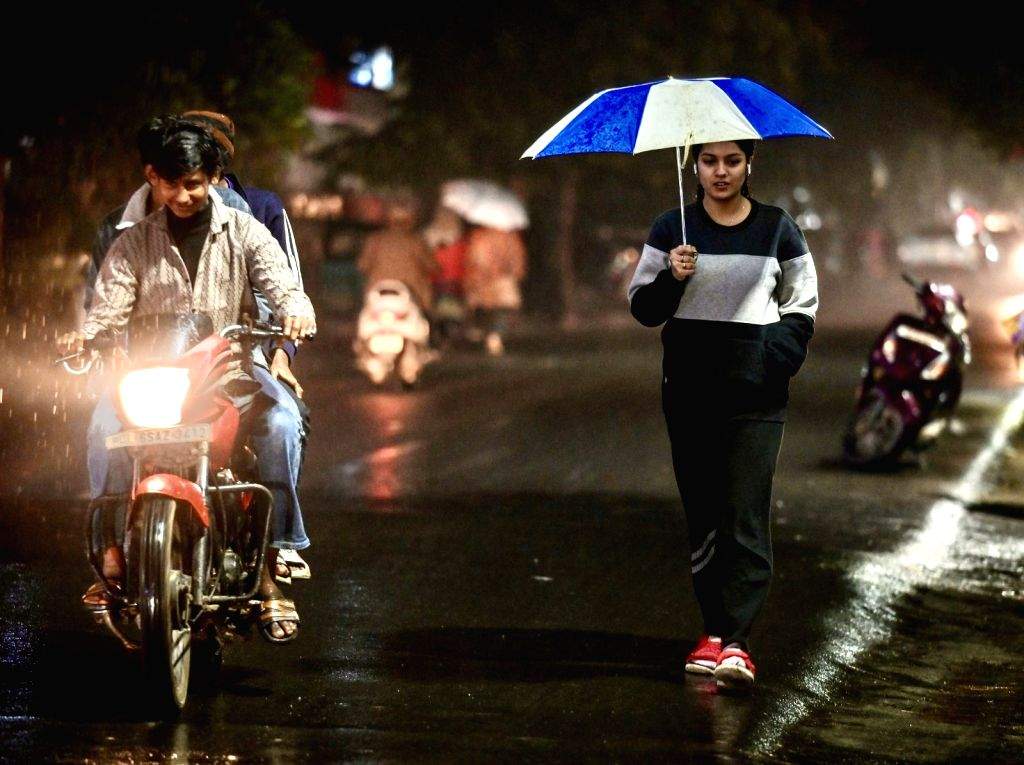 Commuters navigate a rain-soaked street amid rainfall