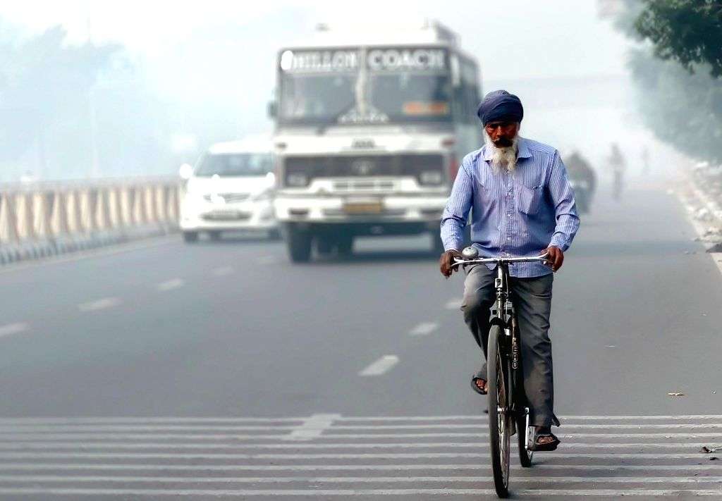 Commuters ride along a road amid hazy weather conditions