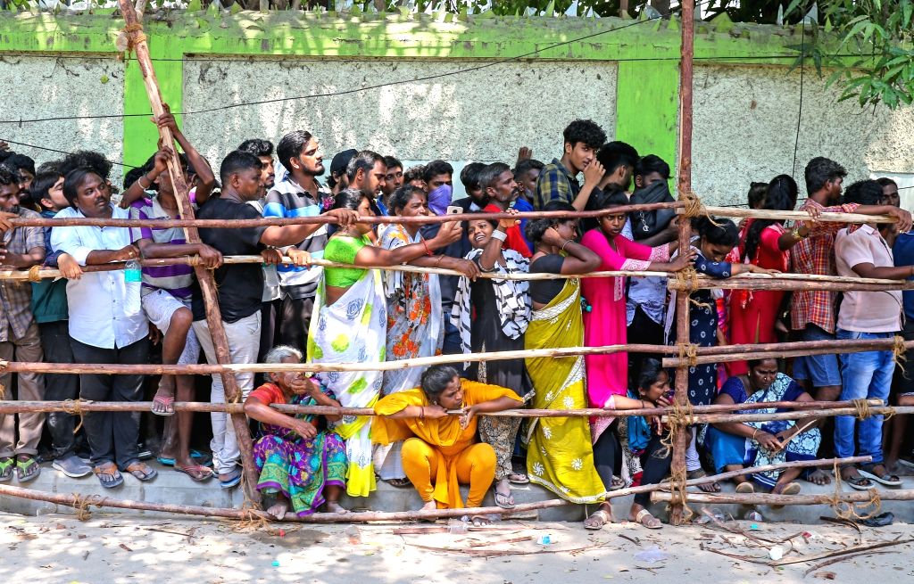 Cricket fans stand in a queue waiting to buy a ticket