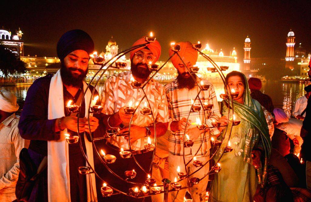 Devotees light diyas at the illuminated Golden Temple