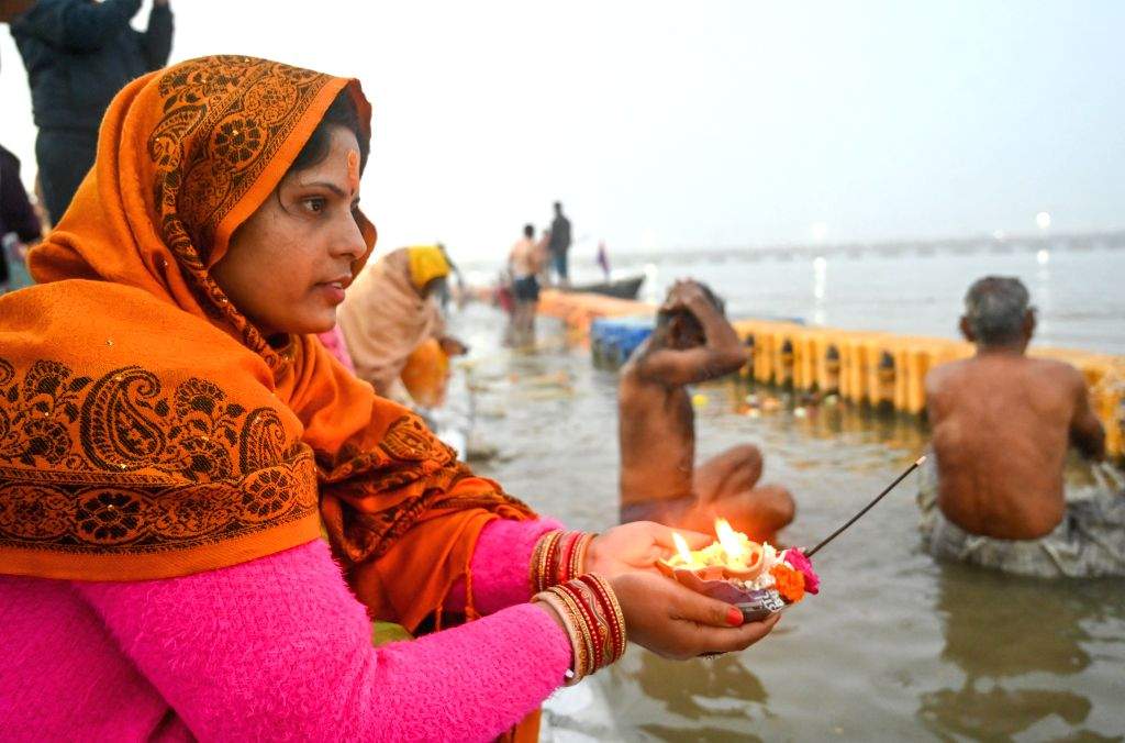 Devotees offer prayer with a diya at the Triveni Sangam