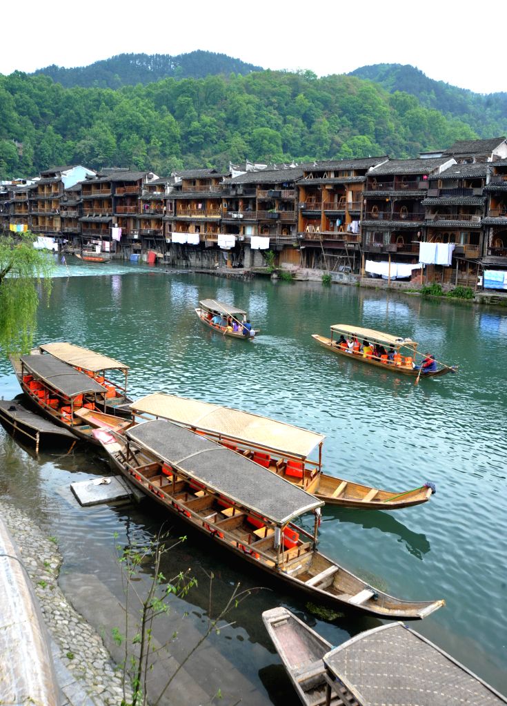 Tourists travel by boats at the Fenghuang ancient town, in Xiangxi ...