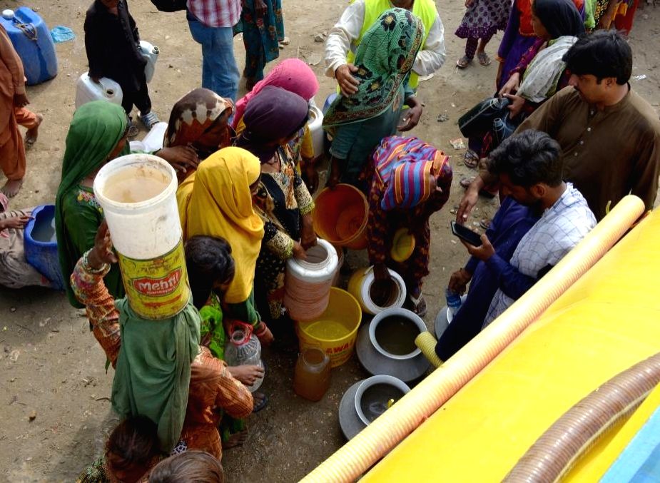 Flood-affected people take drinking water from a water tanker in Jamshoro