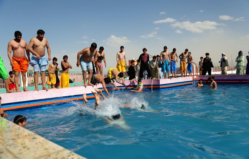 Afghan men jump into a swimming pool to cool themselves