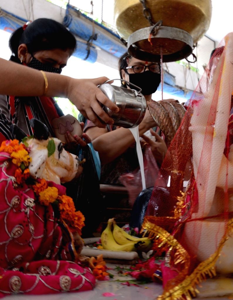 Hindu devotees perform rituals pouring milk and water on a Shiva Lingam ...