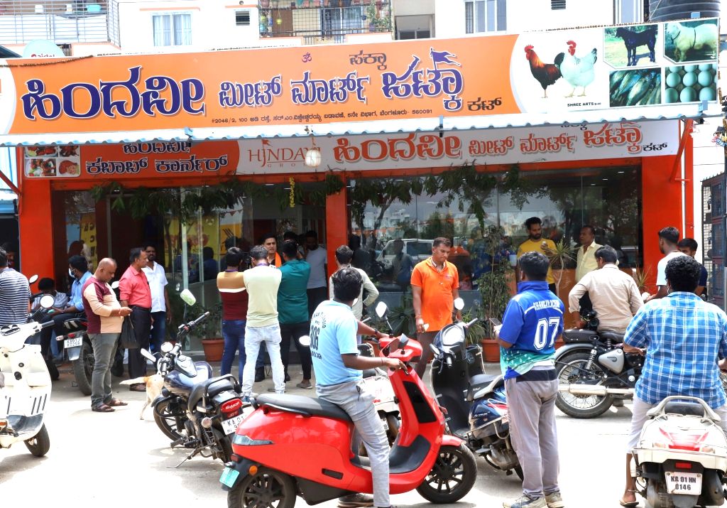 Hindu people stand outside a meat shop to purchase 'Jhatka cut meat