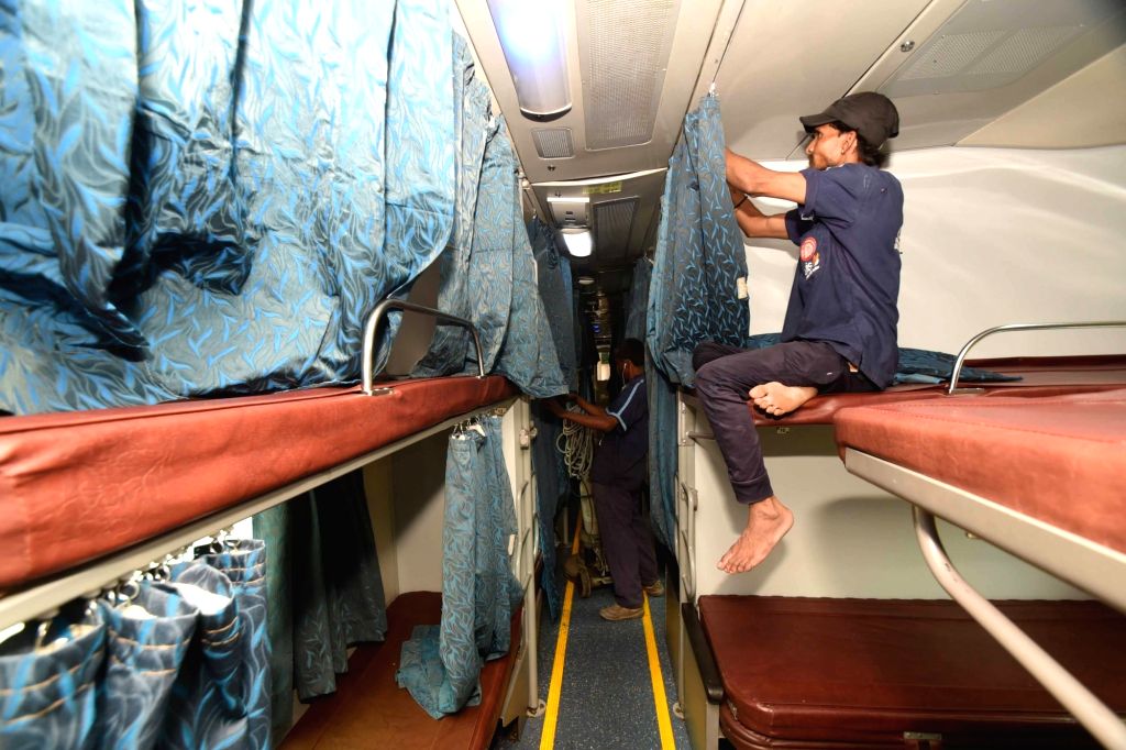 Indian Railways employees work to install curtains for the coach.