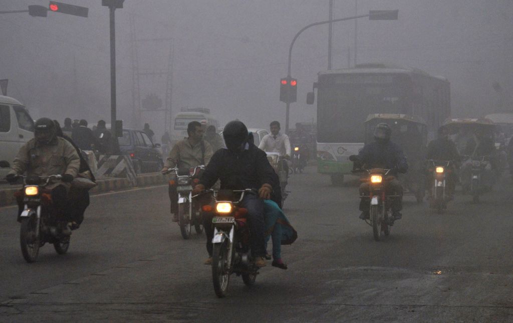 Vehicles move on road during a heavy fog in eastern Pakistan's Lahore