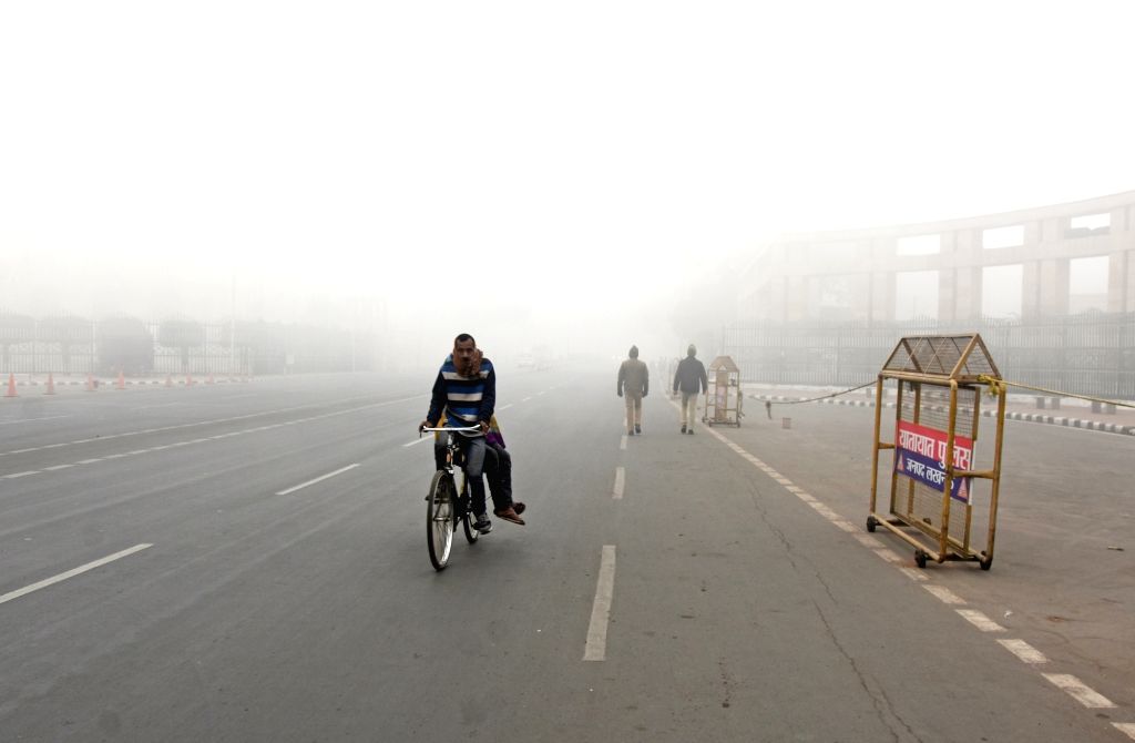 : Lucknow : A man rides a bicycle during dense fog on a cold winter morning