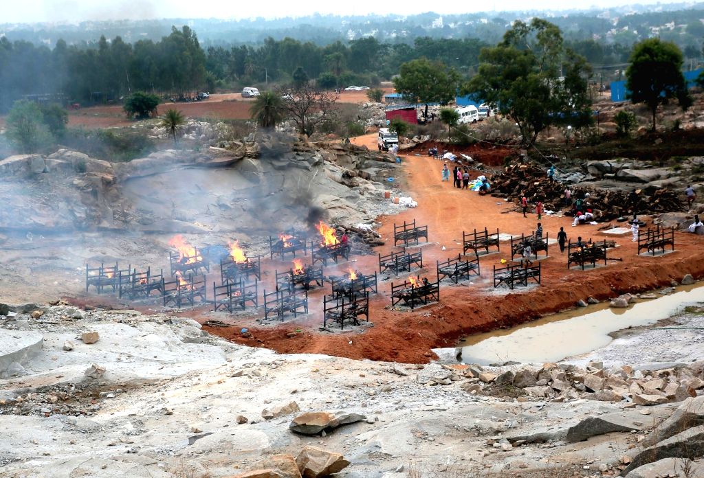 Multiple funeral pyres of those who died of COVID-19 burn at Giddenahalli